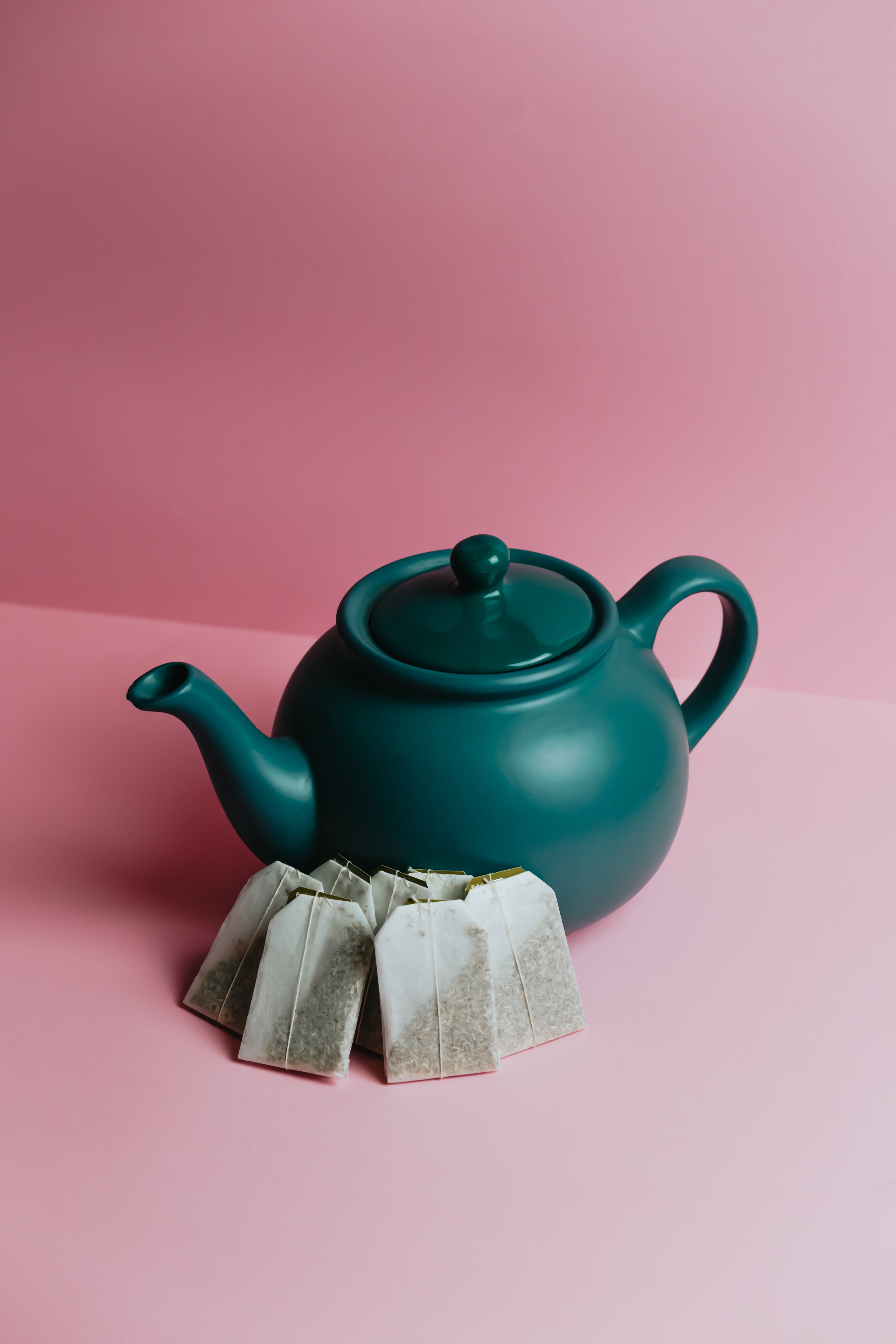 Green Teapot Sits On A Pink Background With Fresh Tea Bags - Image Abyss